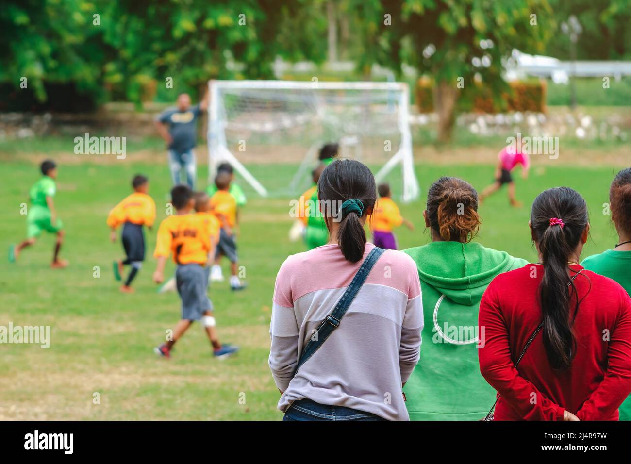 Back view of Moms watch and cheering their sons playing football in ...