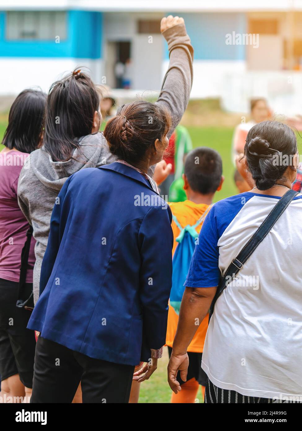 Back view of Moms watch and cheering their sons playing football in ...