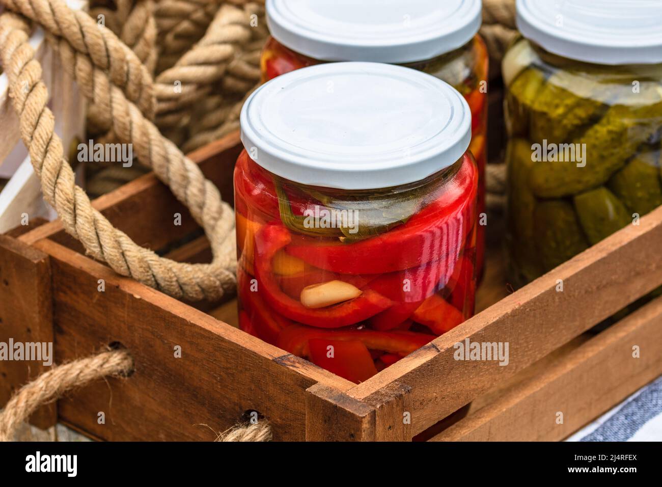 Wooden crate with glass jars with pickled red bell peppers and pickled ...