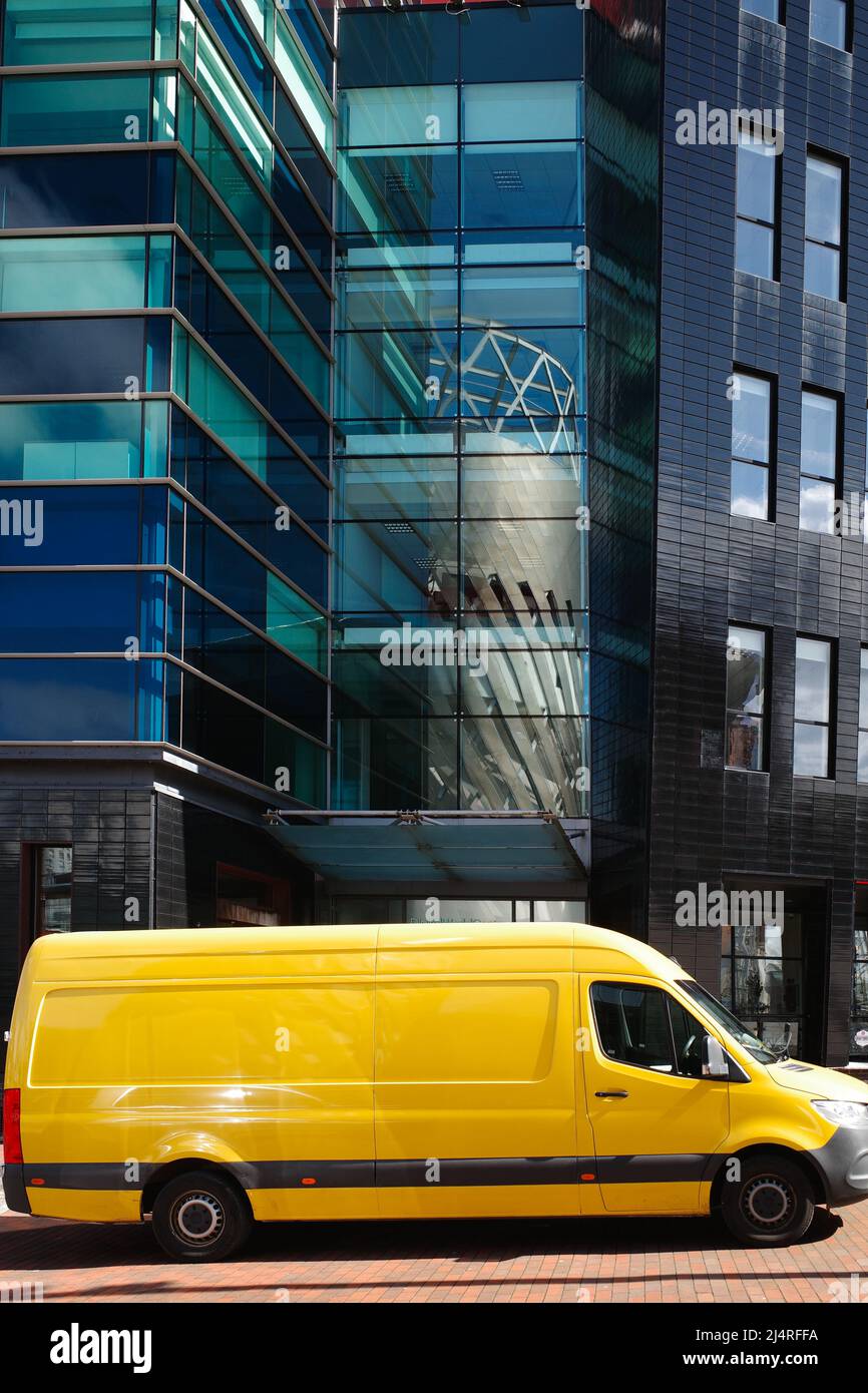 yellow parcel delivery van outside modern glass fronted office building ...