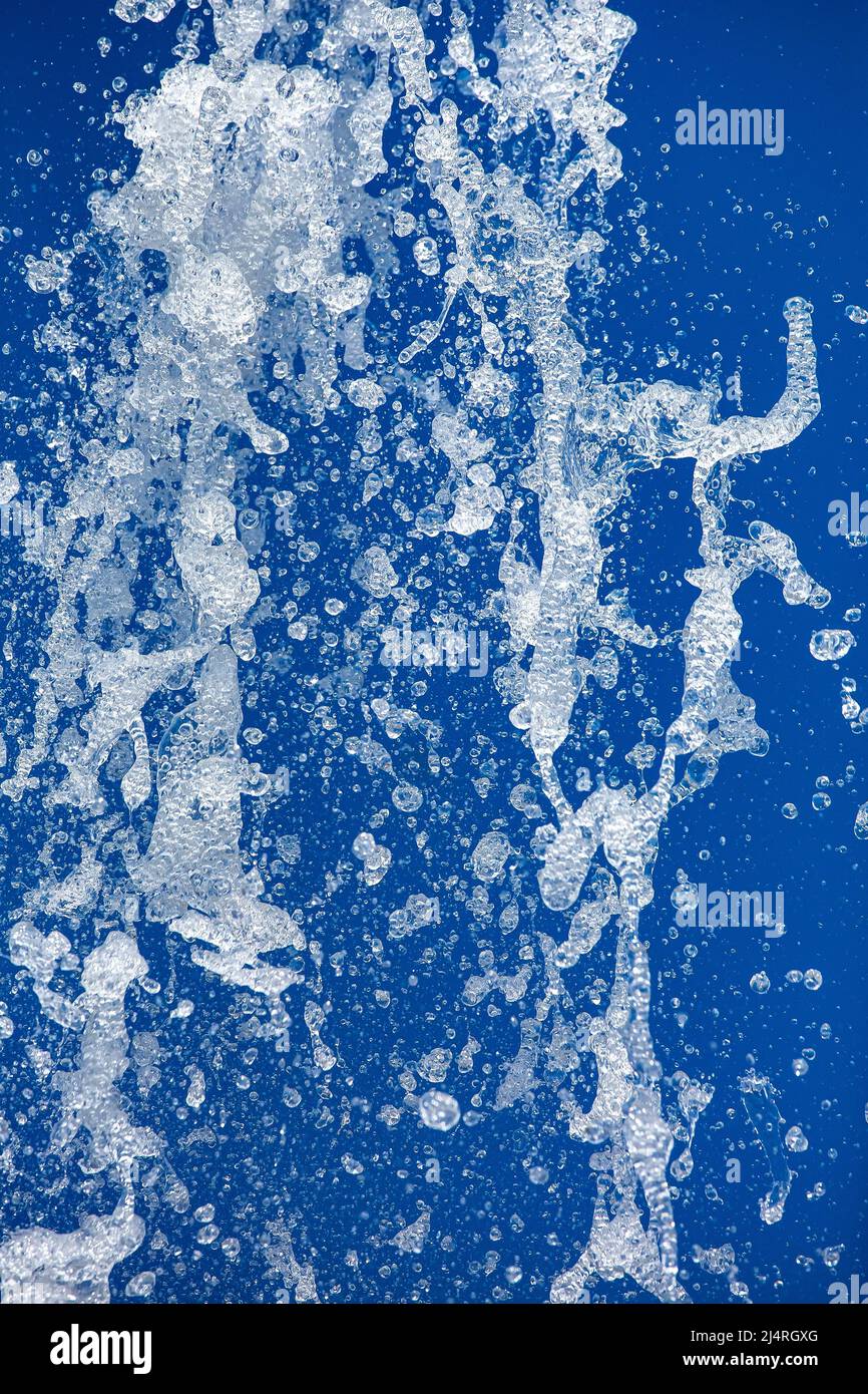 a jet of water sprayed under pressure from a fountain against a blue ...