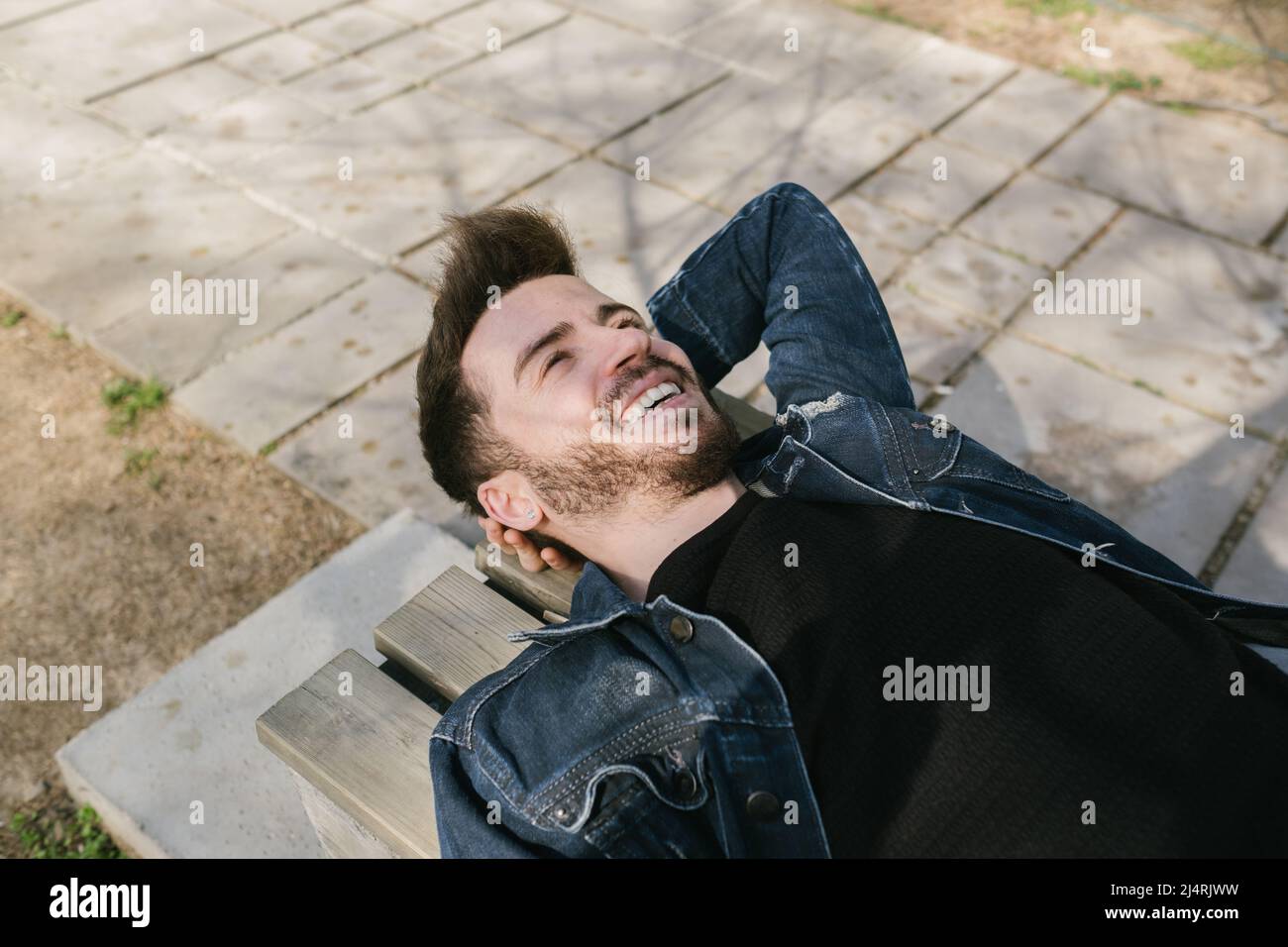 Handsome man relaxing on wooden park bench lounge in city park. Happy ...