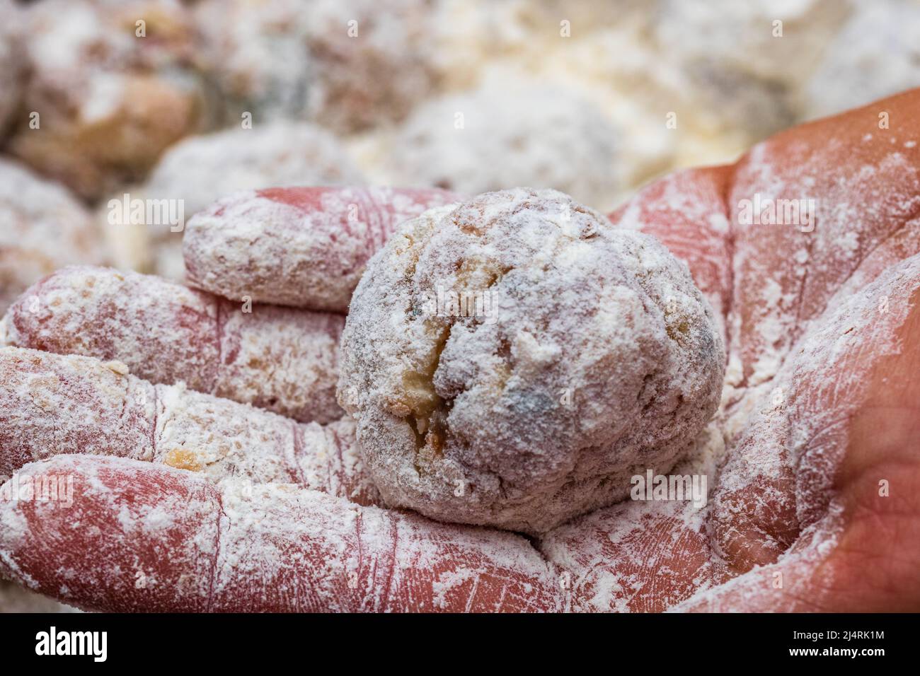 Raw meatballs coated in flour ready for frying. Hand holding meatball ...
