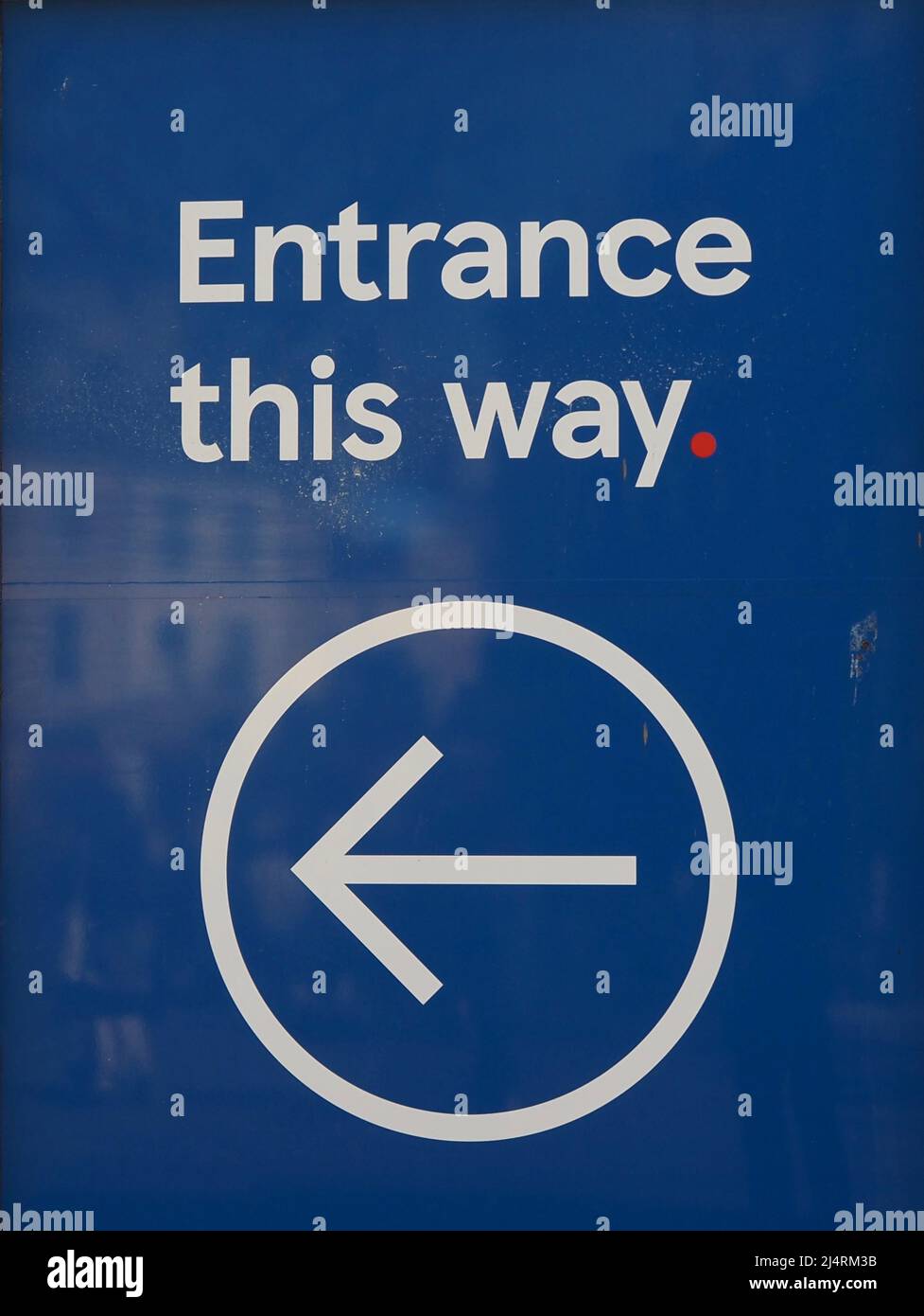 Blue sign directing to entrance on left Stock Photo - Alamy