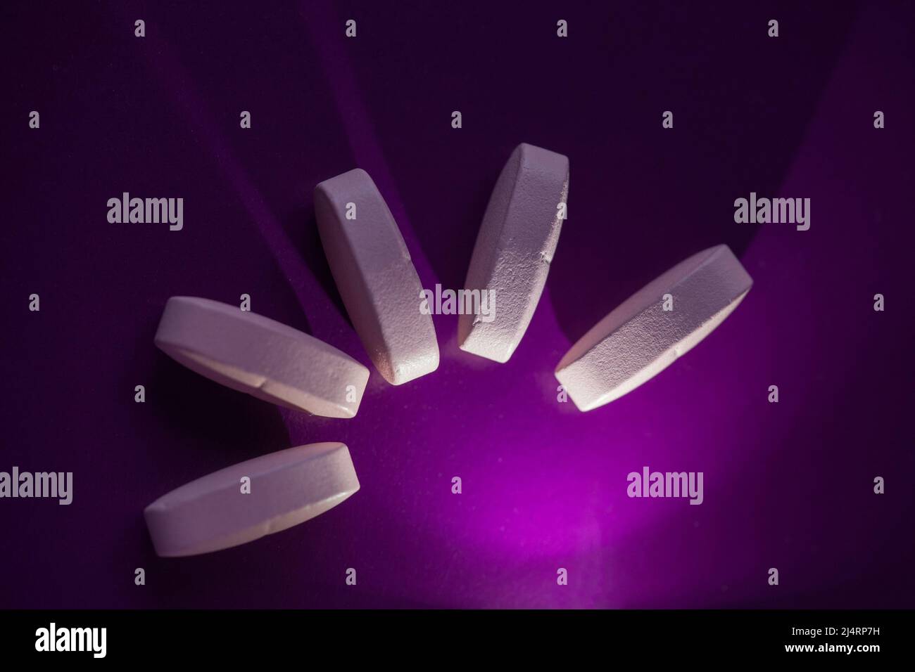 Long pink pills on the purple background. Medicine and healthcare ...