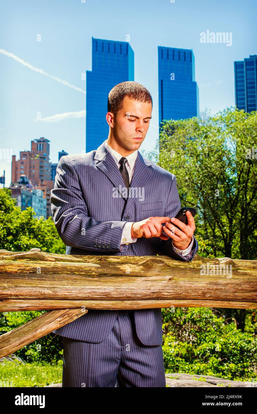 Young businessman texting. Dressing formally in a blue suit, black tie ...