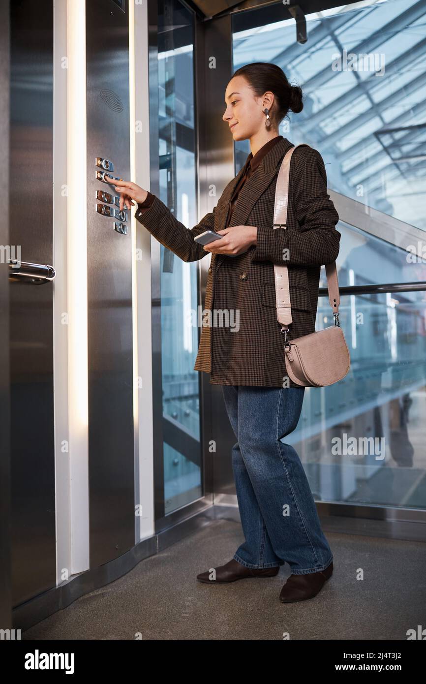 Full length side view at young professional woman pushing button in ...
