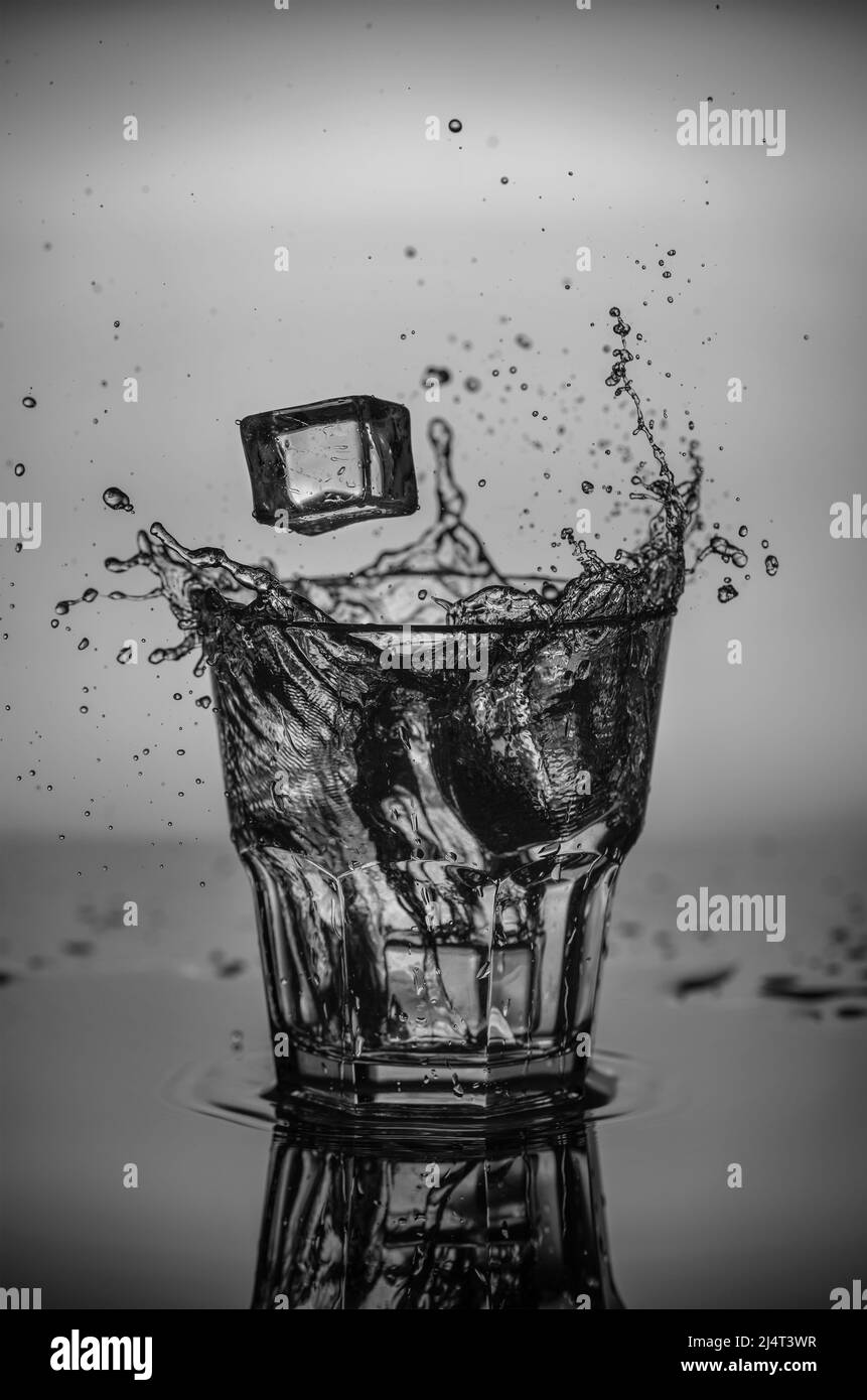 Ice cubes falling into glass of water, close up Stock Photo - Alamy