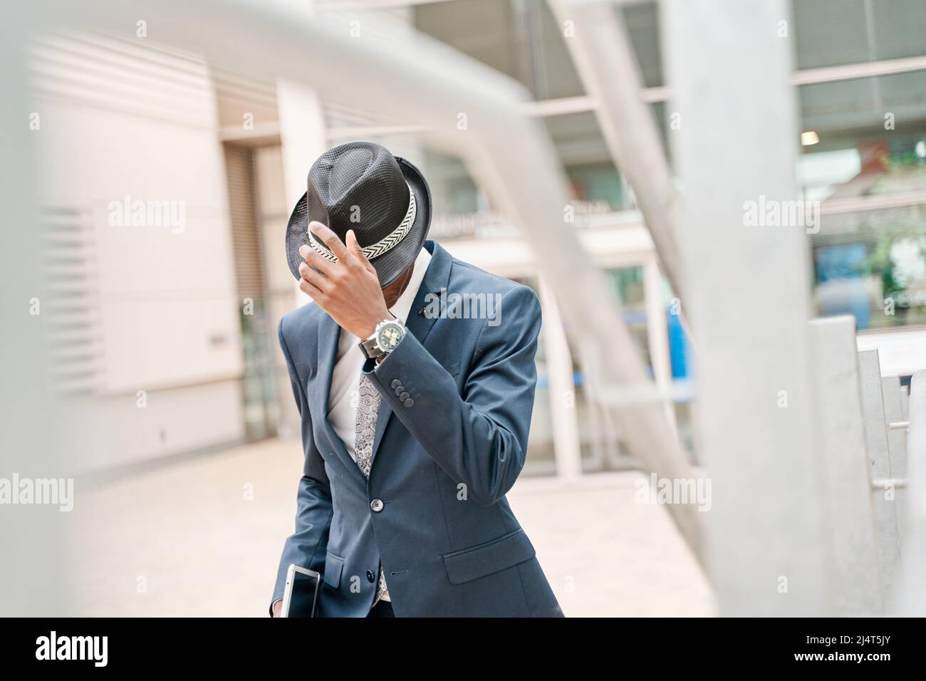 Man in suit hiding face behind his hat. businessman is reflected in ...