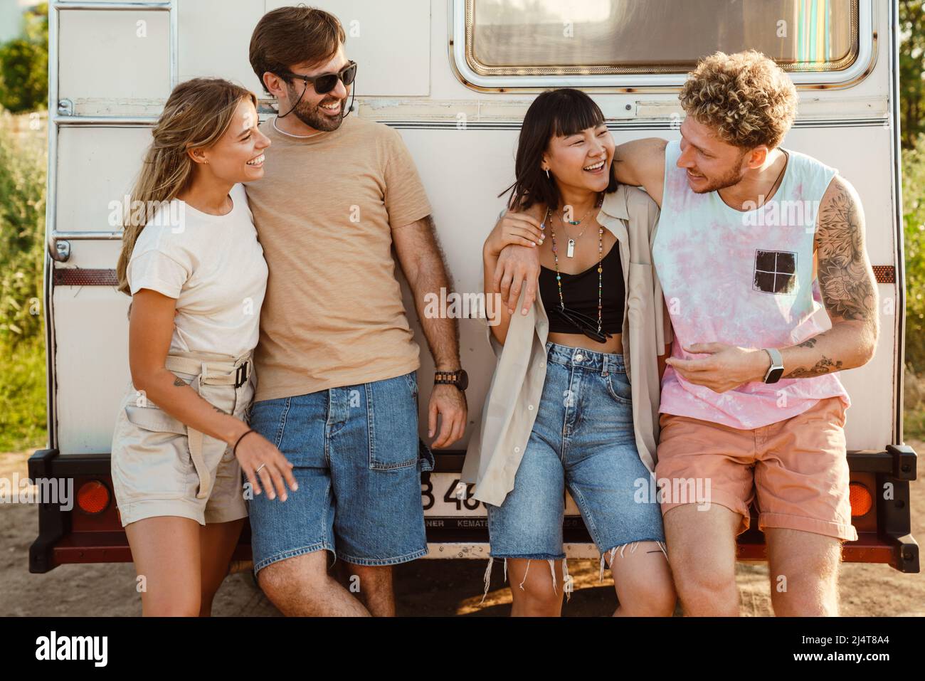 Multiracial two couples talking and laughing together while leaning on ...