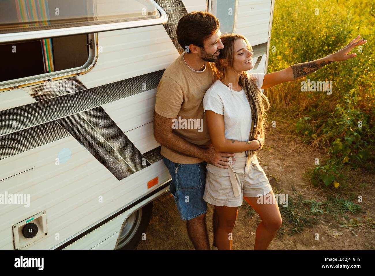 White couple hugging and smiling while standing by trailer outdoors ...