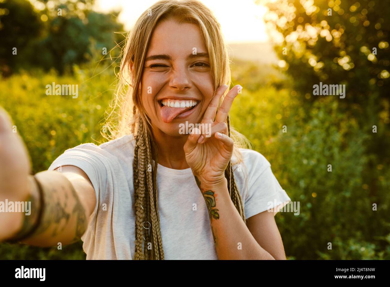 White Young Woman Showing Her Tongue While Taking Selfie Photo Outdoors