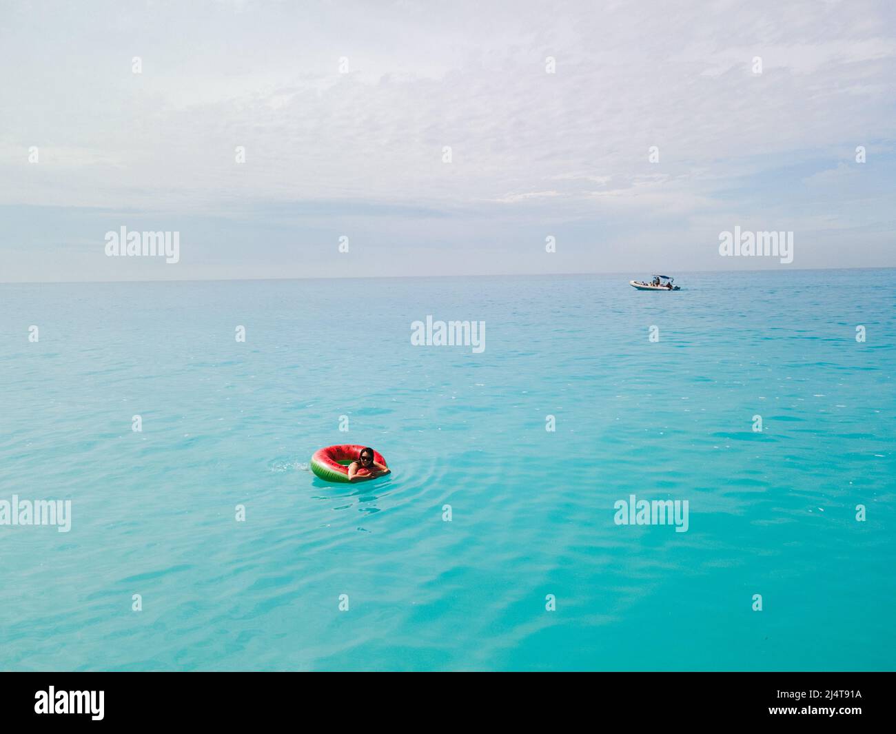 overhead view of woman floating on inflatable ring in blue sea water ...