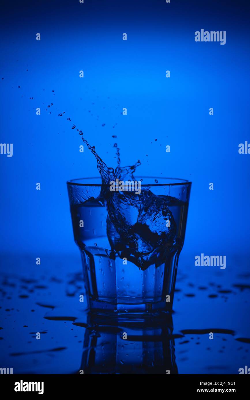 Ice cubes falling into glass of water, close up Stock Photo - Alamy