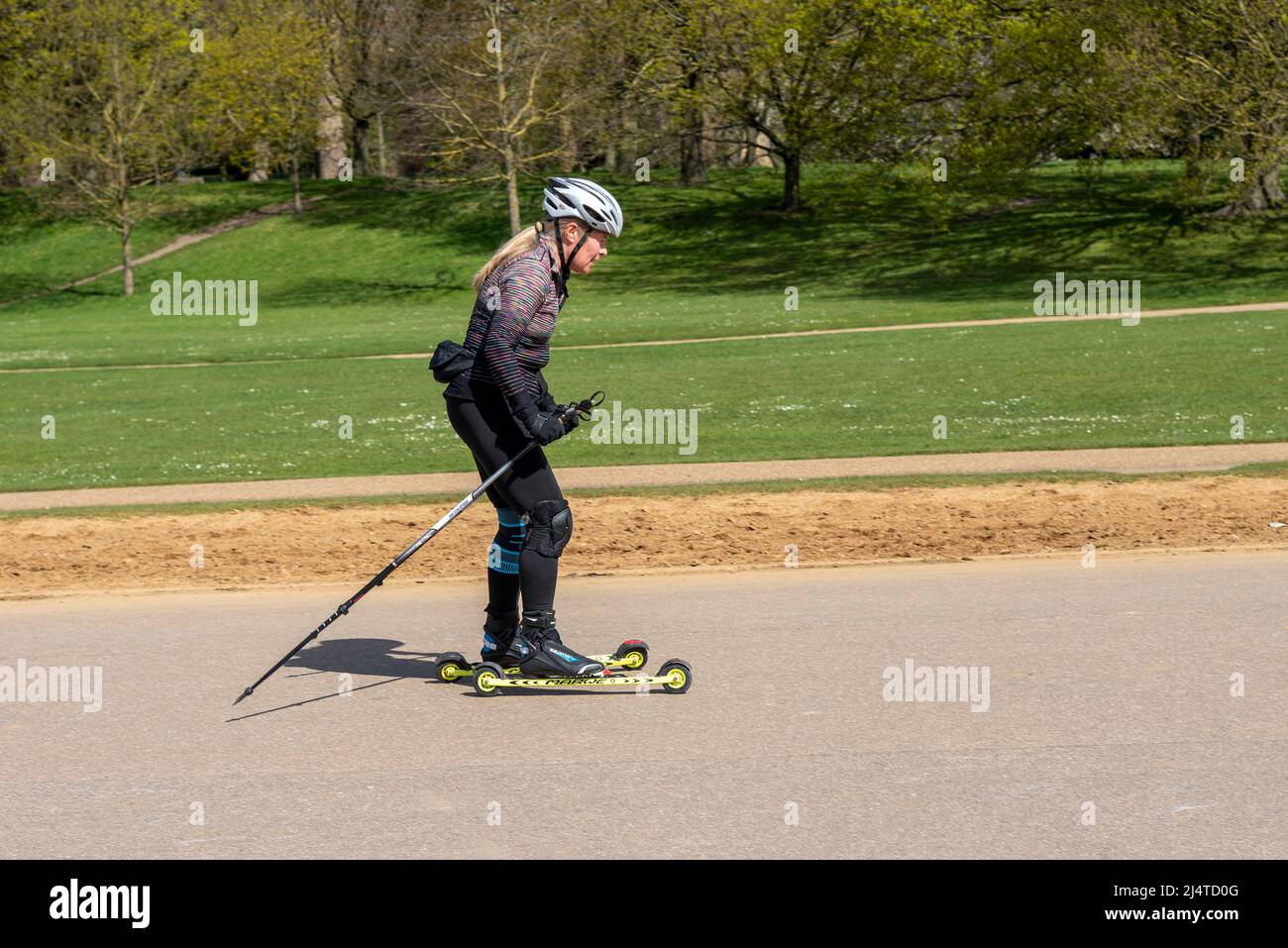 Female roller skiing, or land skiing in a London park on a bright sunny ...