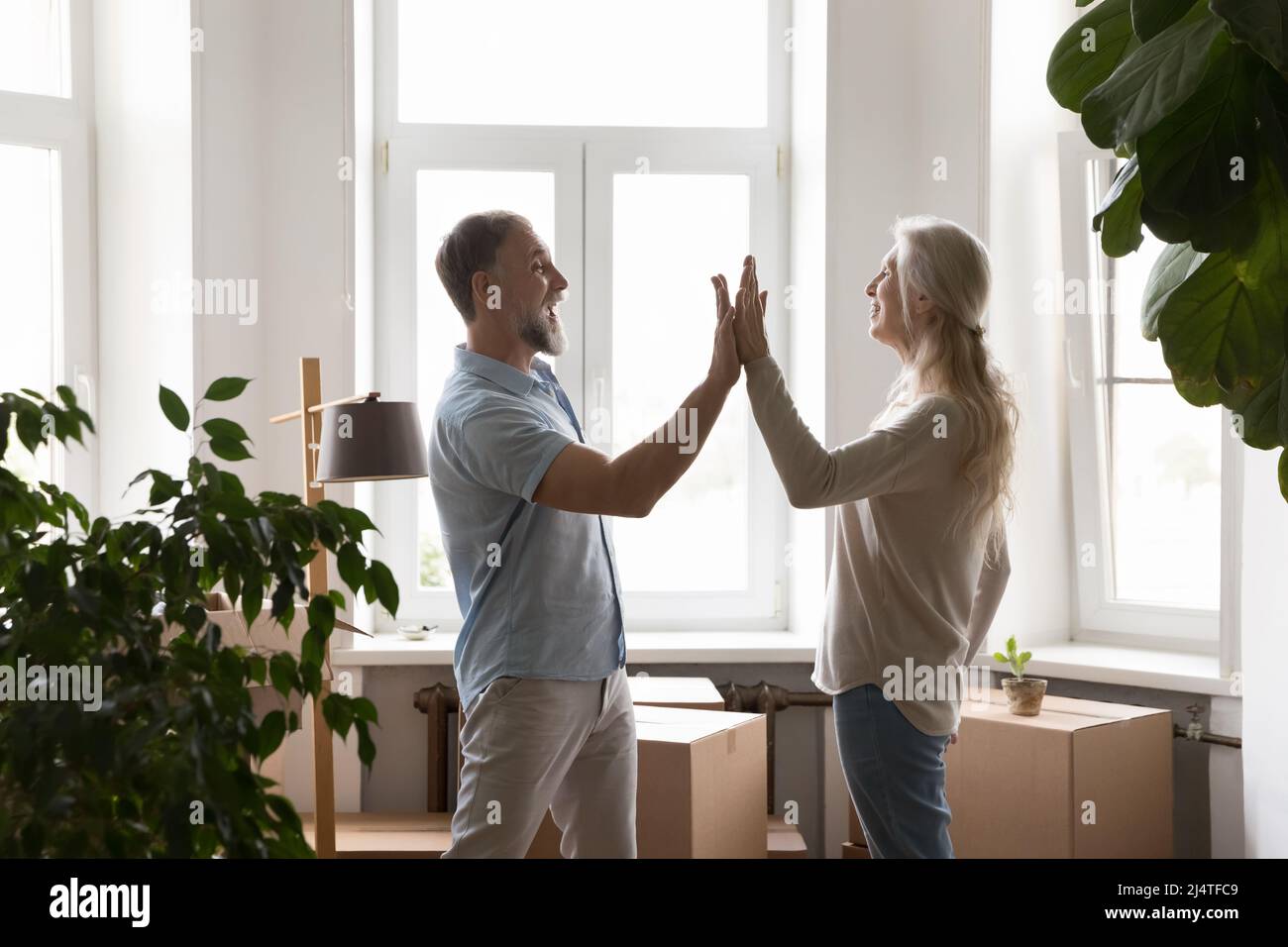 Mature couple accomplish relocation day giving high five feeling happy ...