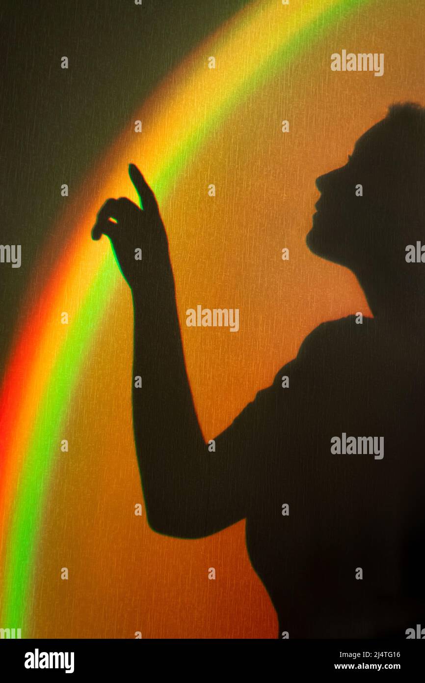 Shadow of woman. Rainbow reflection of sunbeam on wall. Hand touches ...