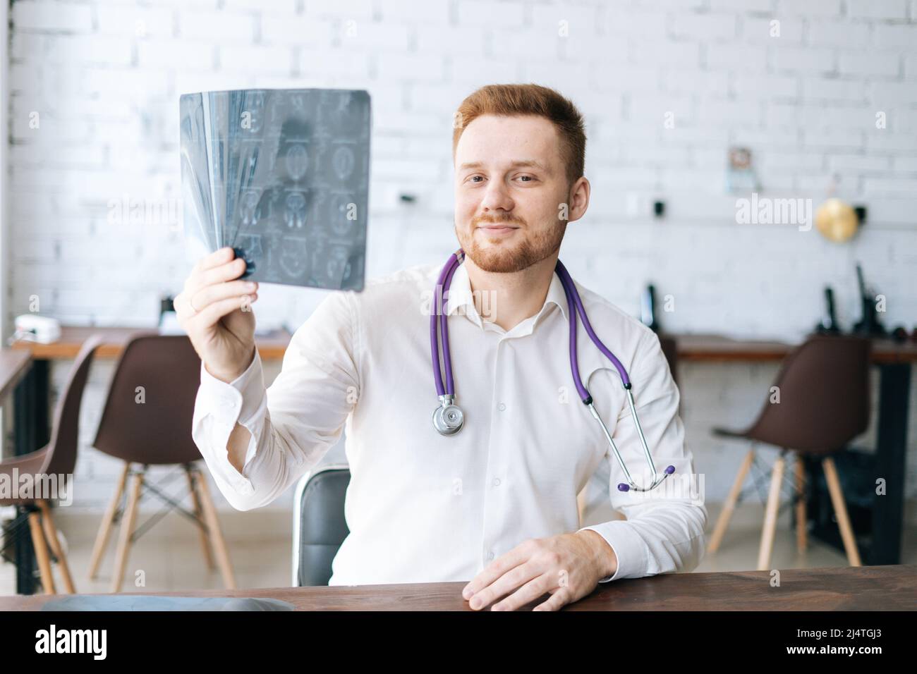 Portrait of positive male doctor wearing white uniform examining brain ...