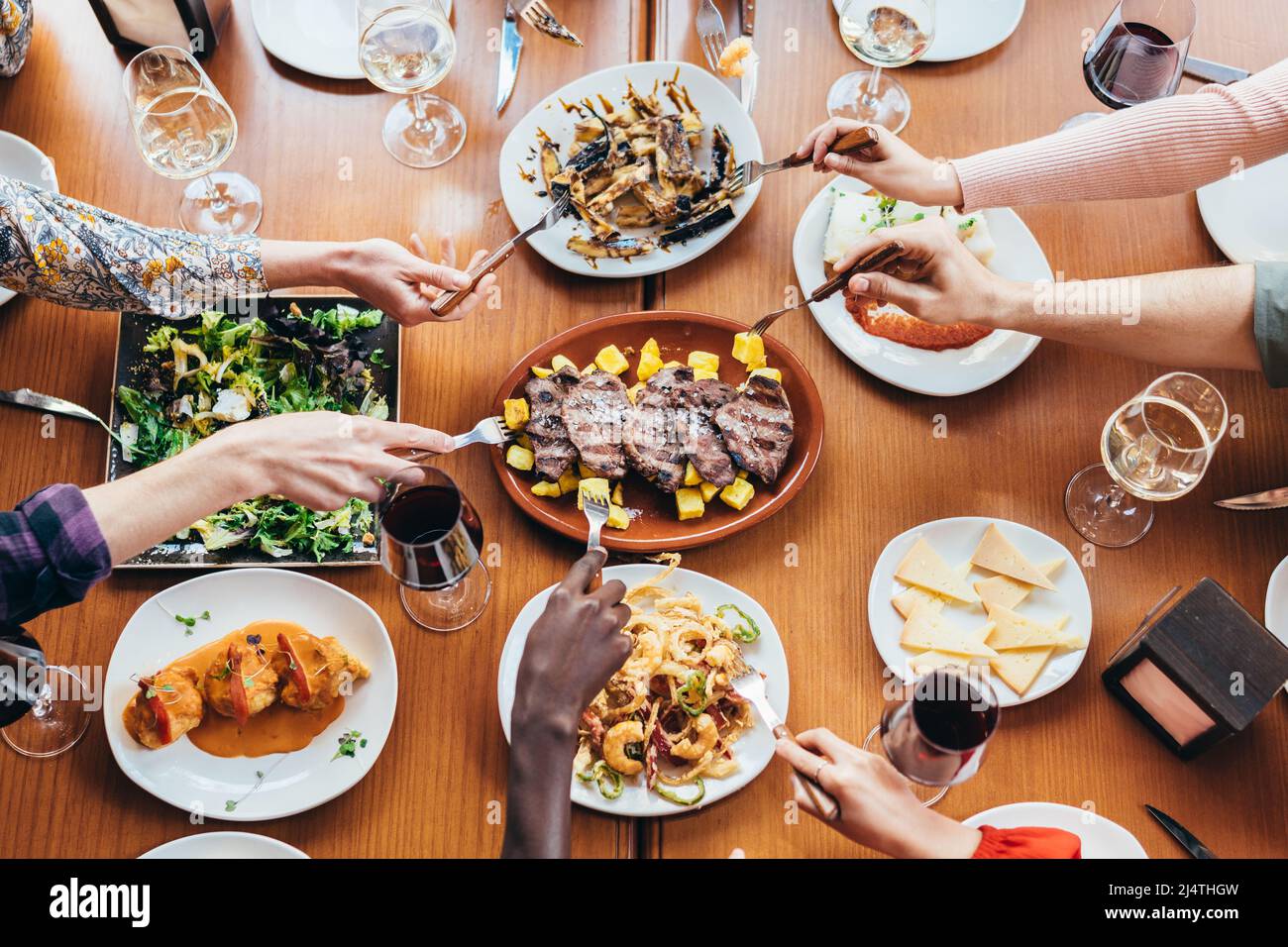 zenithal shot of an interracial group of friends poking food with their ...