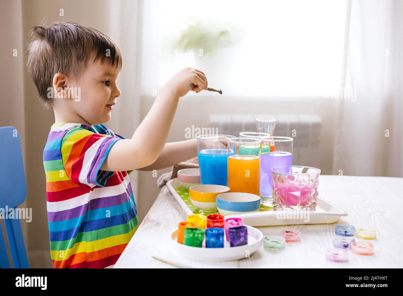 Cute baby boy learning mixing different colors with water and paint in ...