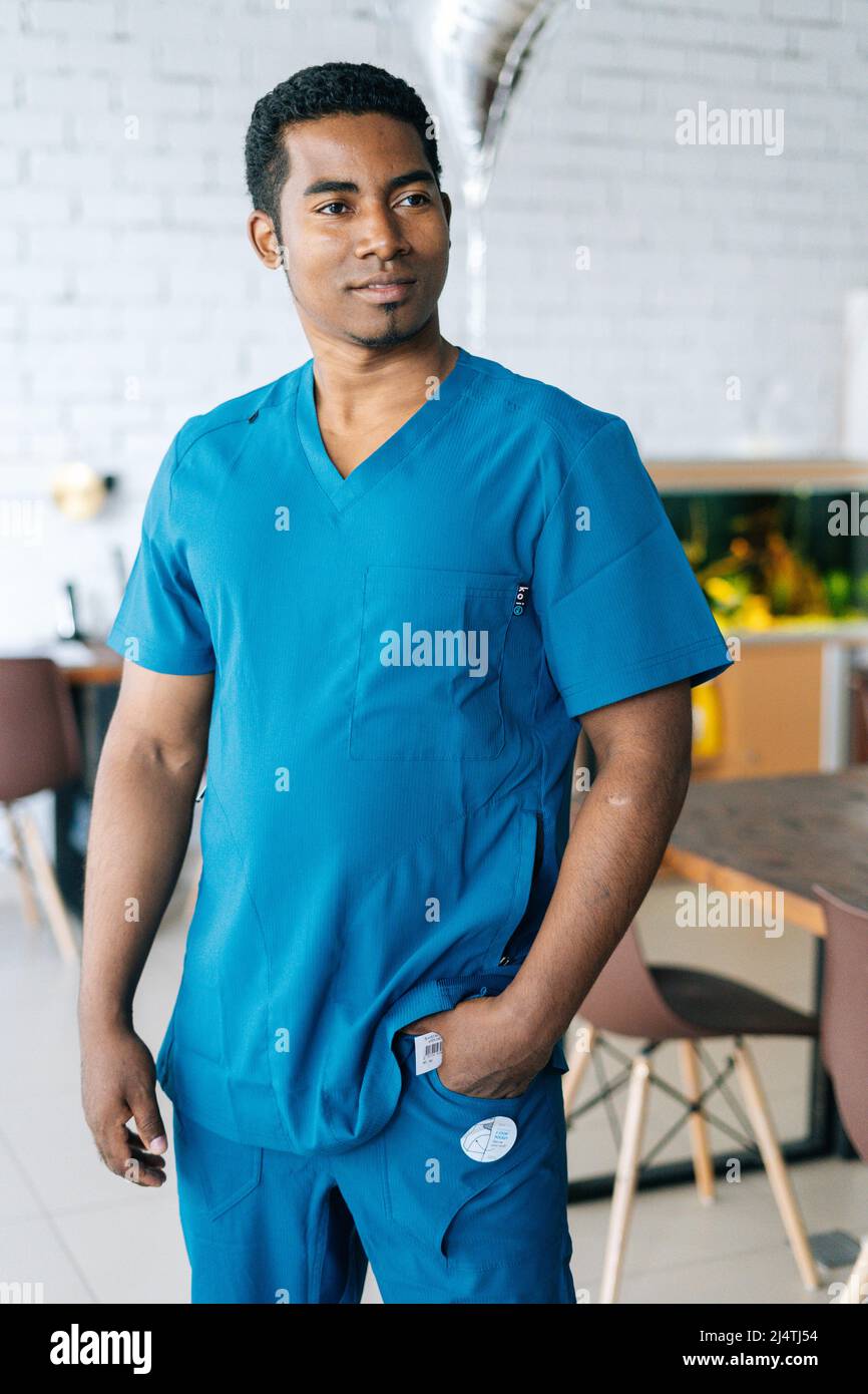 Vertical portrait of handsome African American male doctor wearing blue ...