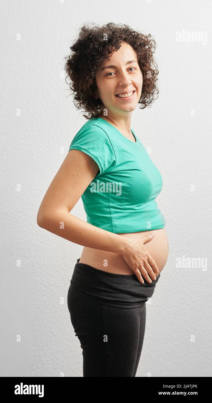 Peaceful pregnant caucasian woman hugging her tummy in front of ...