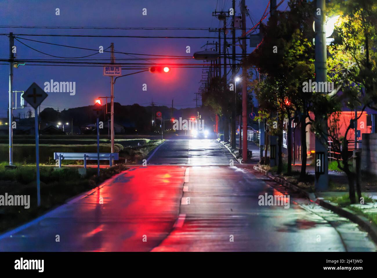Lights reflect off wet roadway at rural intersection after dark Stock ...