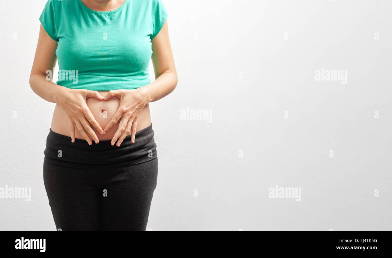 Unrecognizable peaceful pregnant caucasian woman hugging her tummy in ...