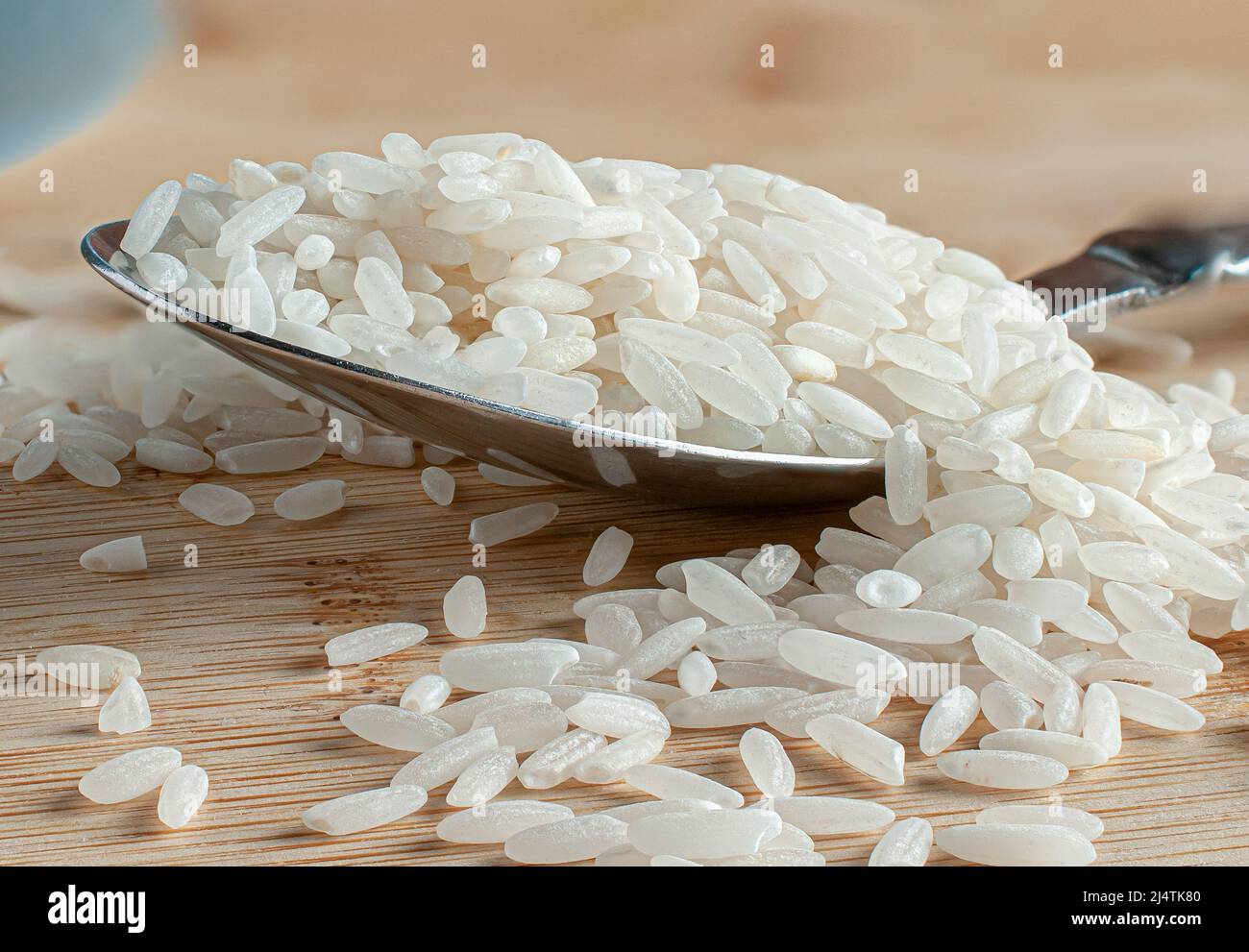 Rice grains in a spoon and on a wooden chopping board. Macro ...