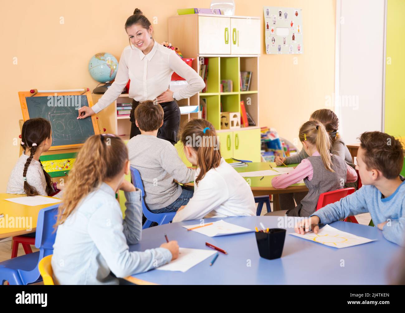 Teacher standing at blackboard in classroom Stock Photo - Alamy