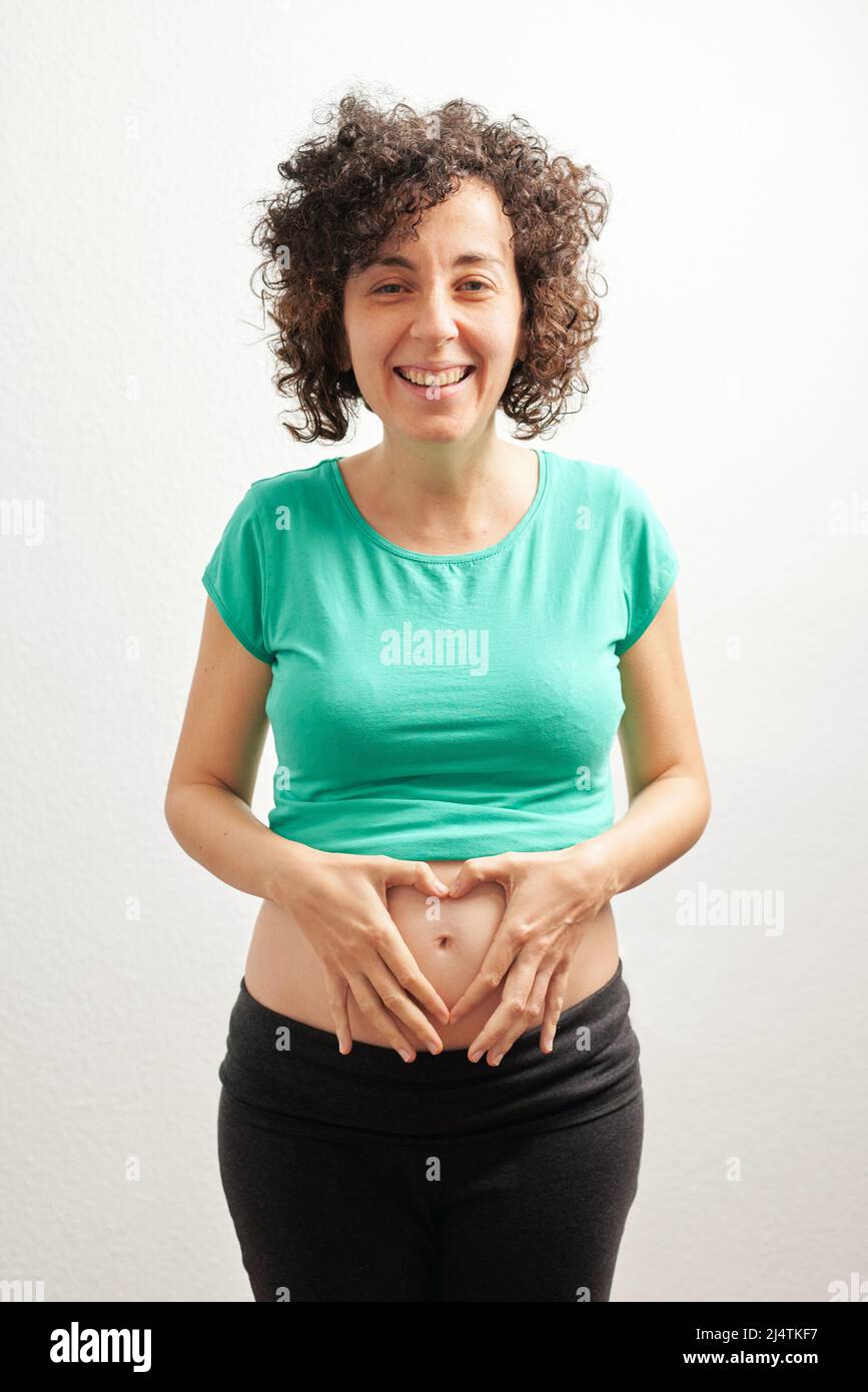 Peaceful pregnant caucasian woman hugging her tummy in front of ...
