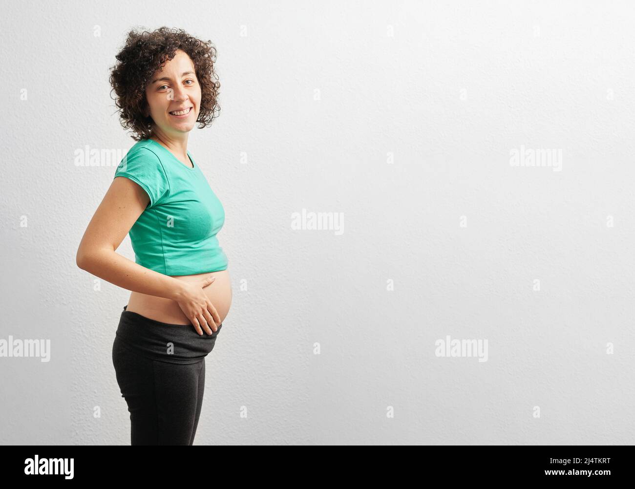 Peaceful pregnant caucasian woman hugging her tummy in front of ...