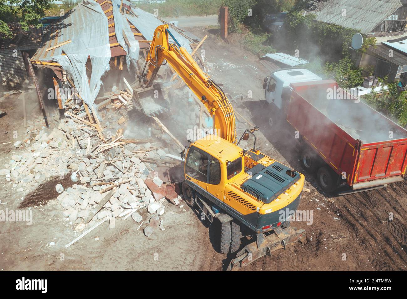 Excavator loads construction waste into truck for removal from ...