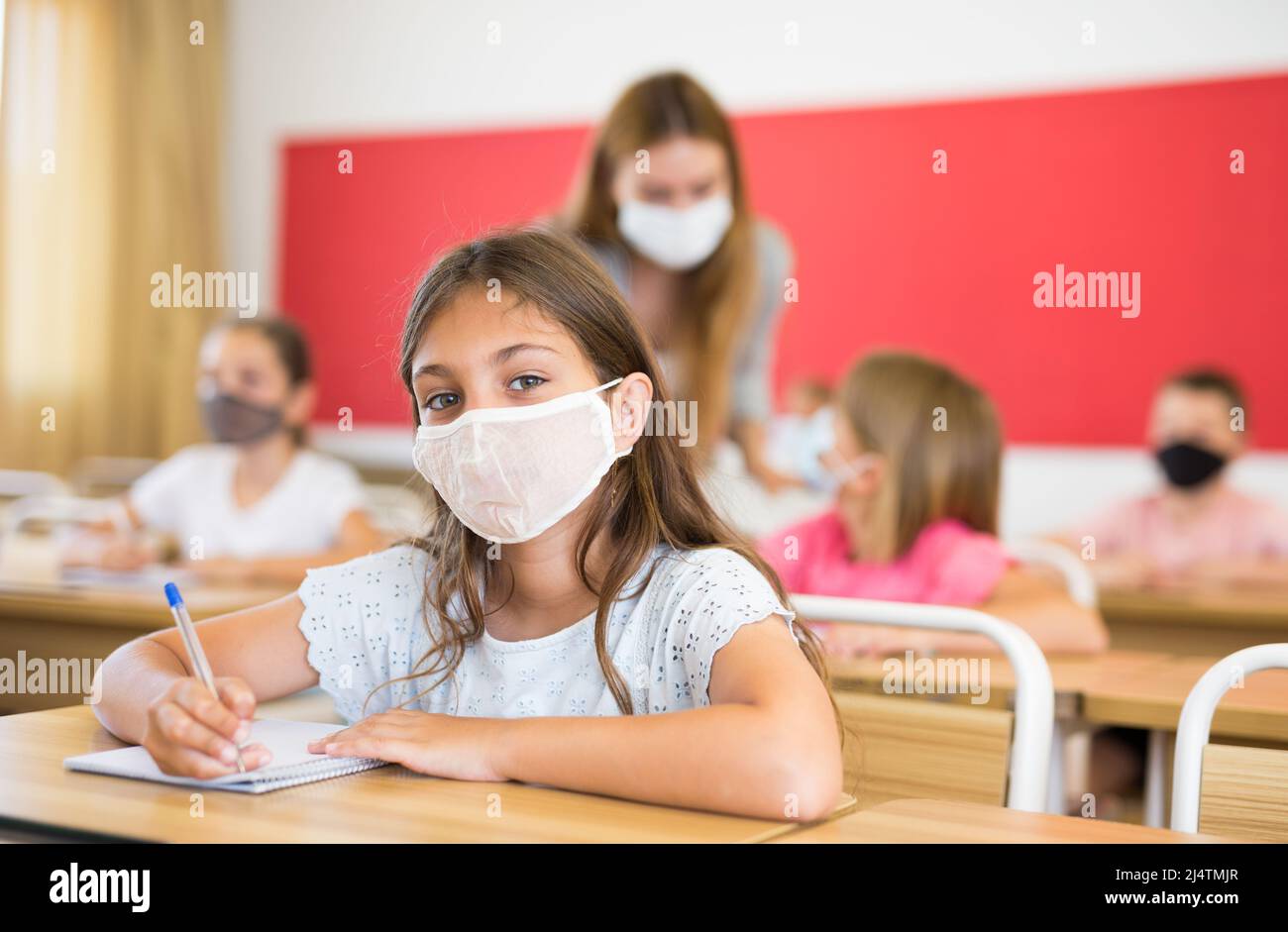 Teacher helping kids to complete exercises Stock Photo - Alamy