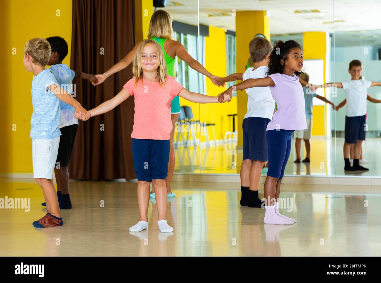 Happy kids and female teacher dancing together in studio at elementary ...