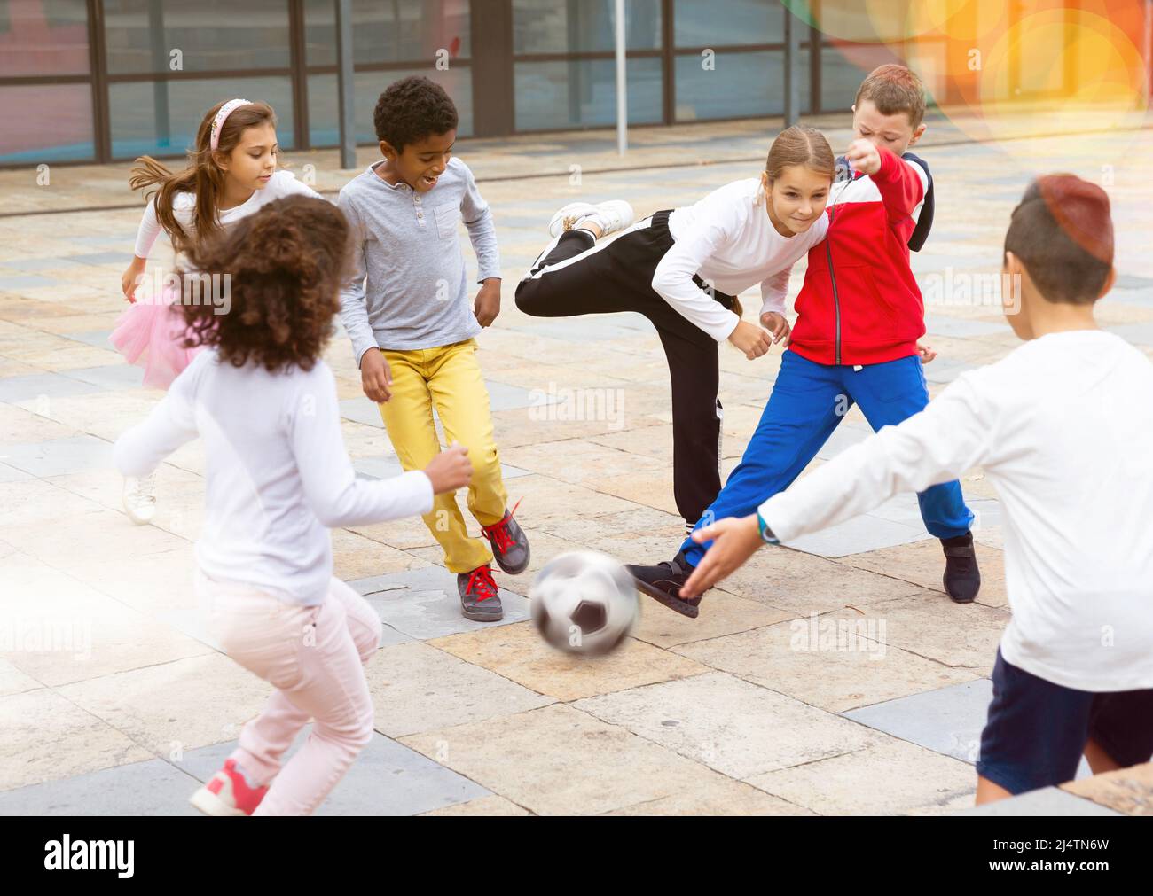 Happy tween girls and boys playing football in schoolyard Stock Photo ...