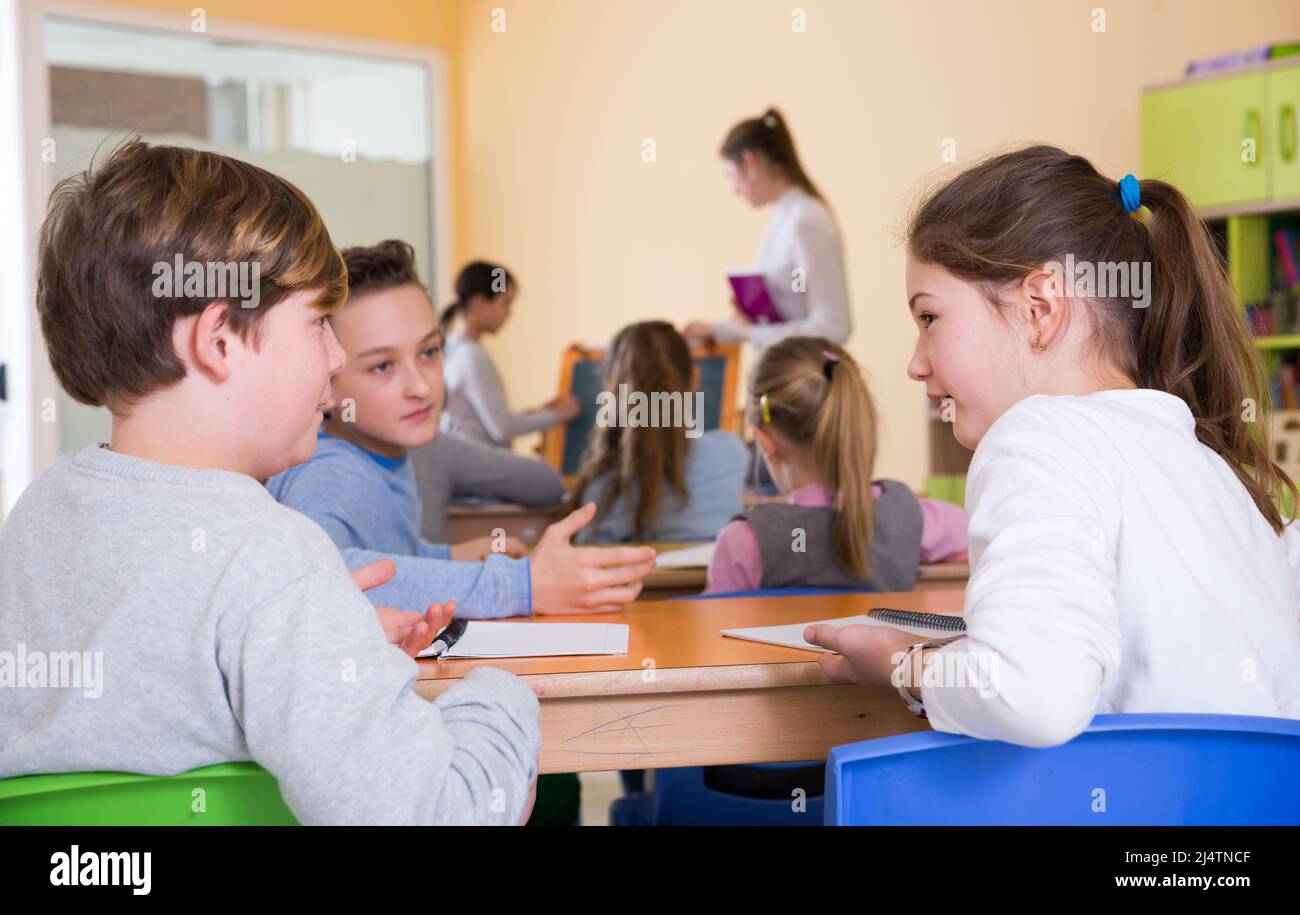 Schoolchildren chatting during lesson Stock Photo - Alamy