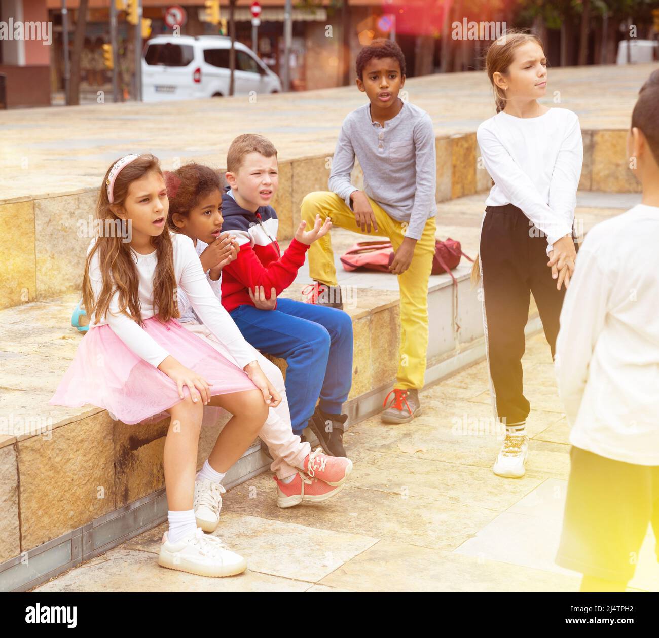 Group of smiling children sitting on stairs and chatting together Stock ...