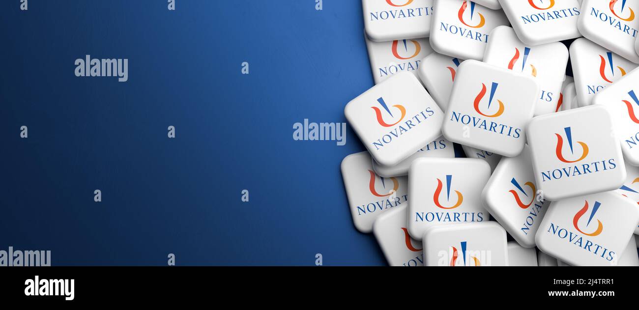 Logos of the Swiss pharmaceutical company Novartis on a heap on a table ...