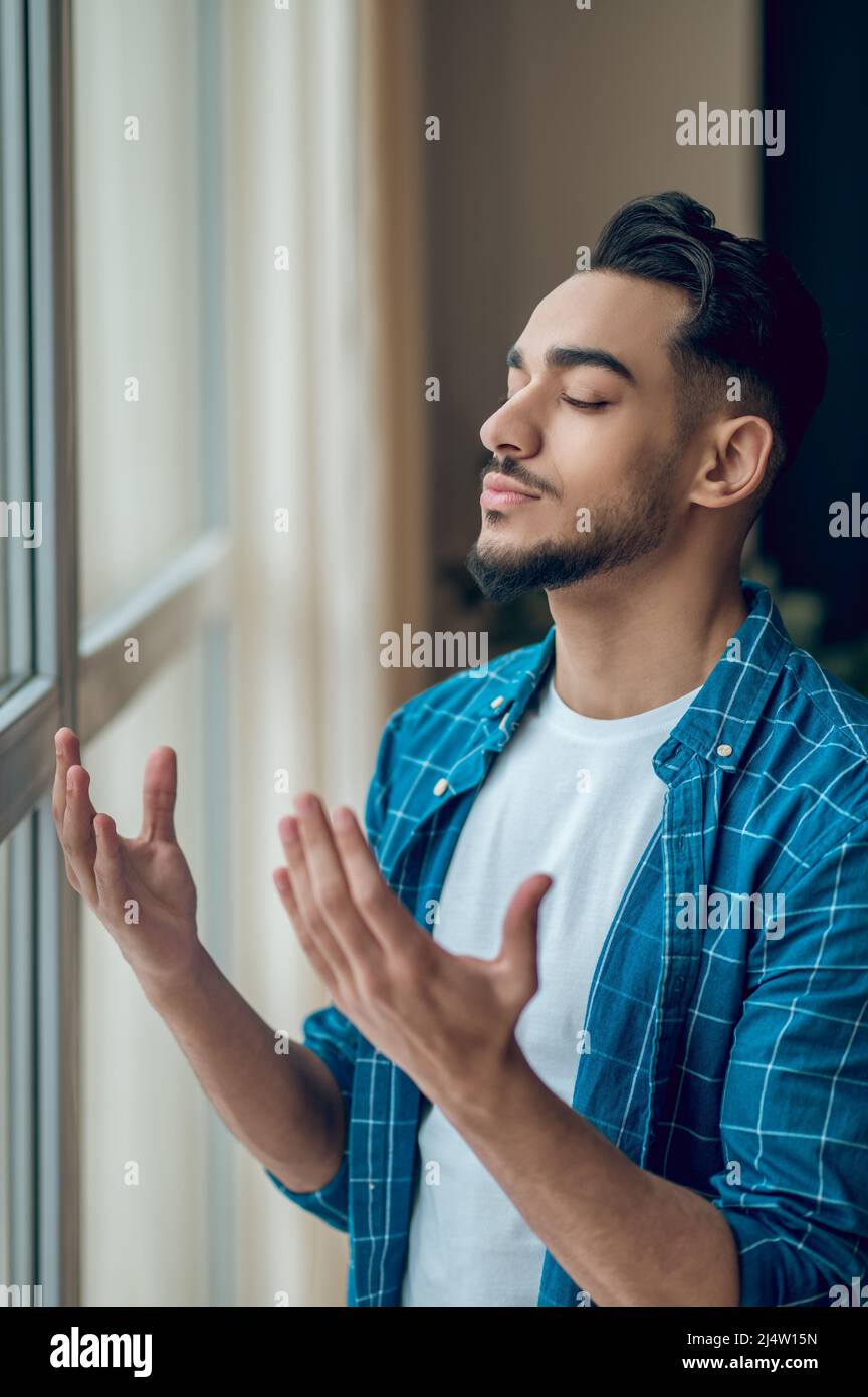 A young bearded man praying with his eyes closed Stock Photo - Alamy