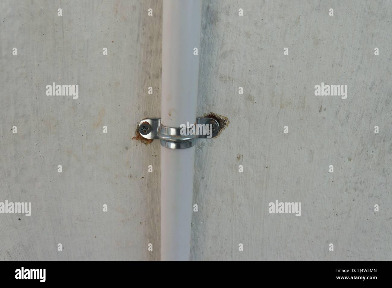 plastic pipe and clamp attached on the wall Stock Photo - Alamy