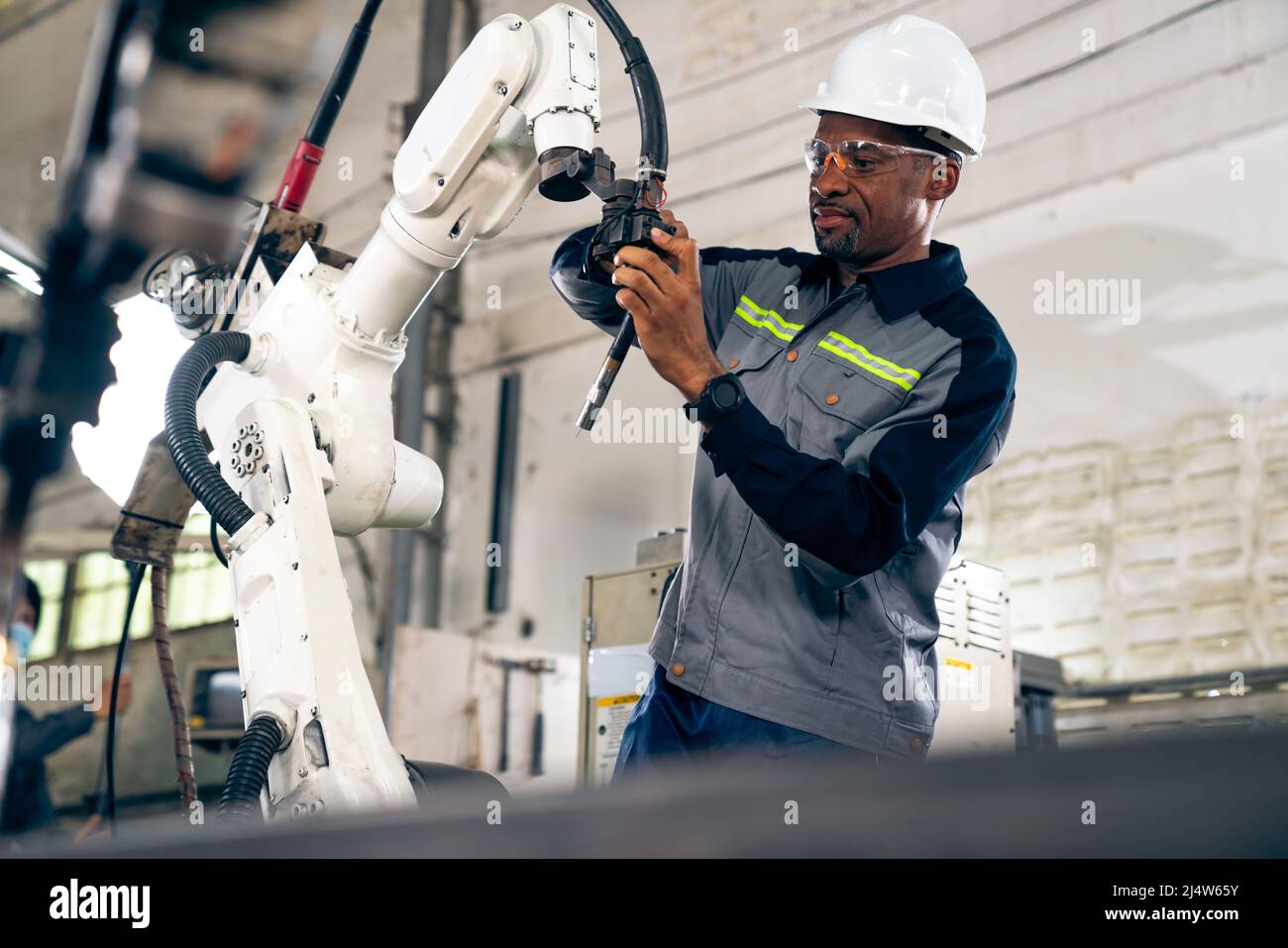 African American factory worker working with adept robotic arm in a ...