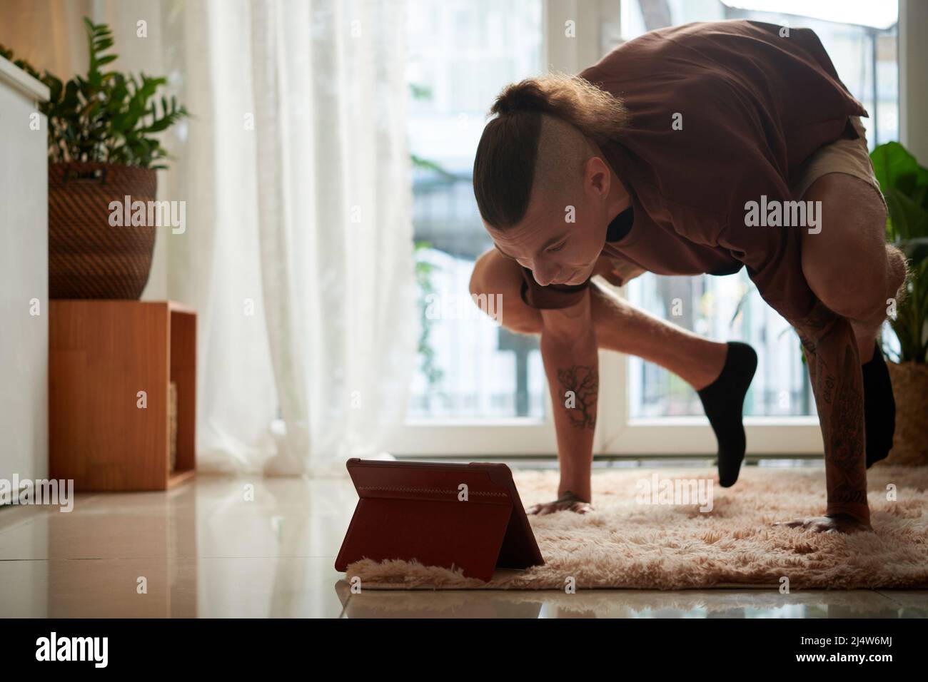 Fit strong young man practicing handstand when following tutorial on ...