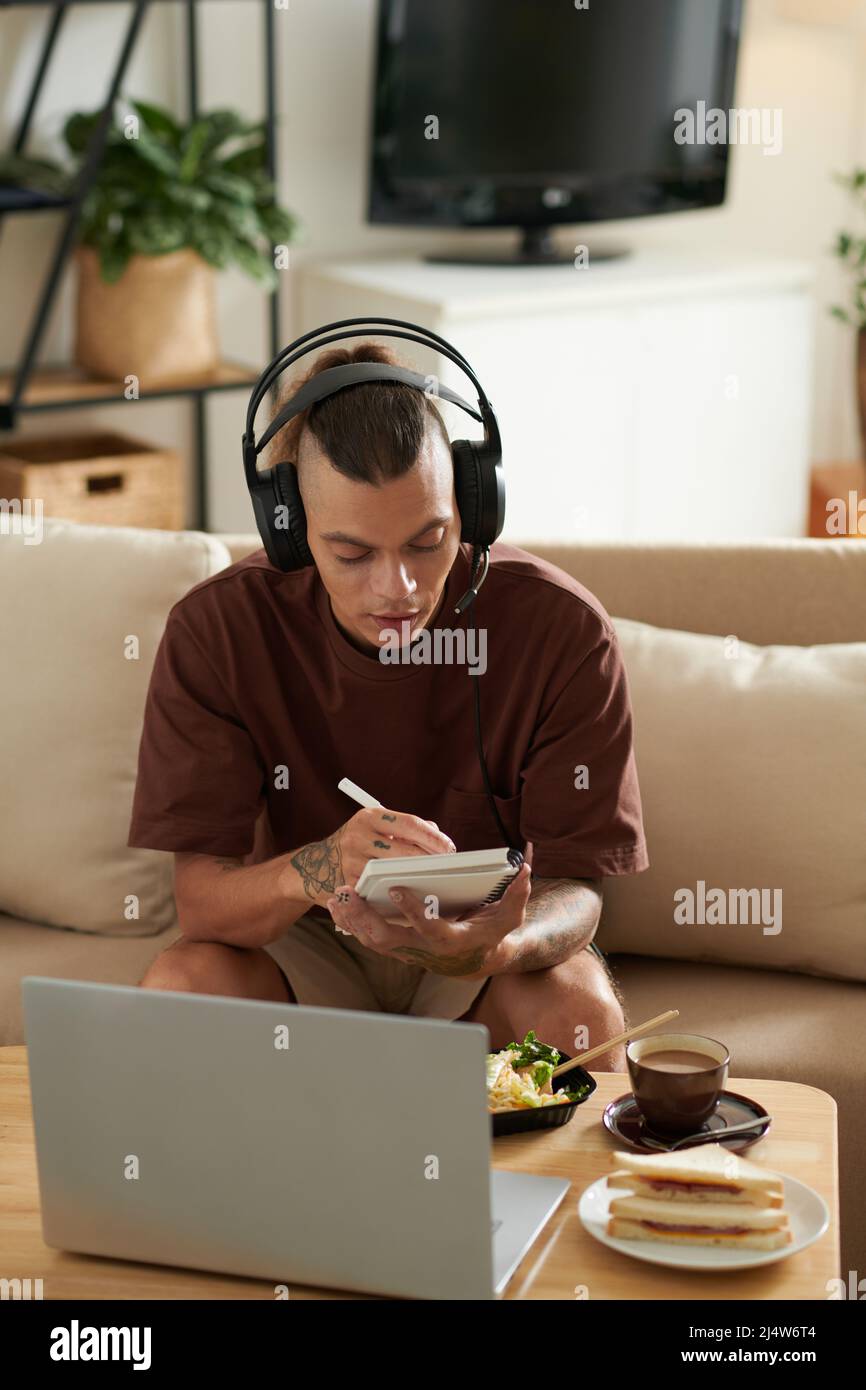 University student eating breakfast when attending online class and ...