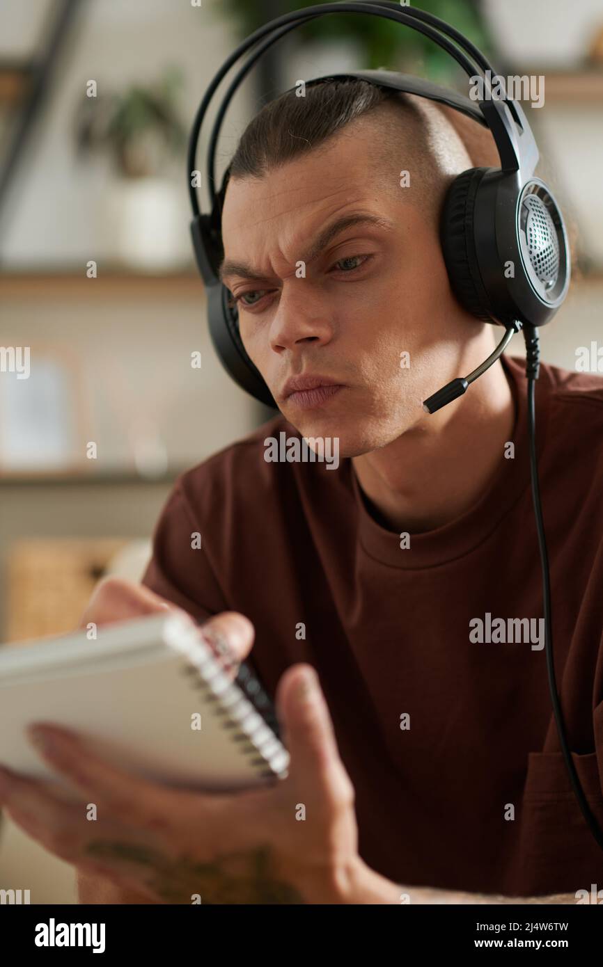 Frowning young man wearing headset when watching video on computer and ...