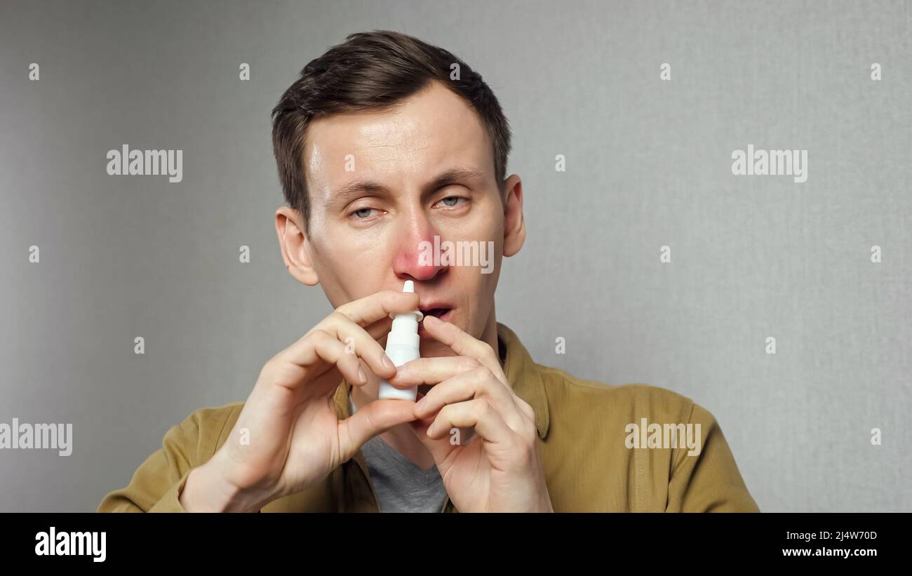 Man sprays nasal medication into nostrils to get relief Stock Photo - Alamy