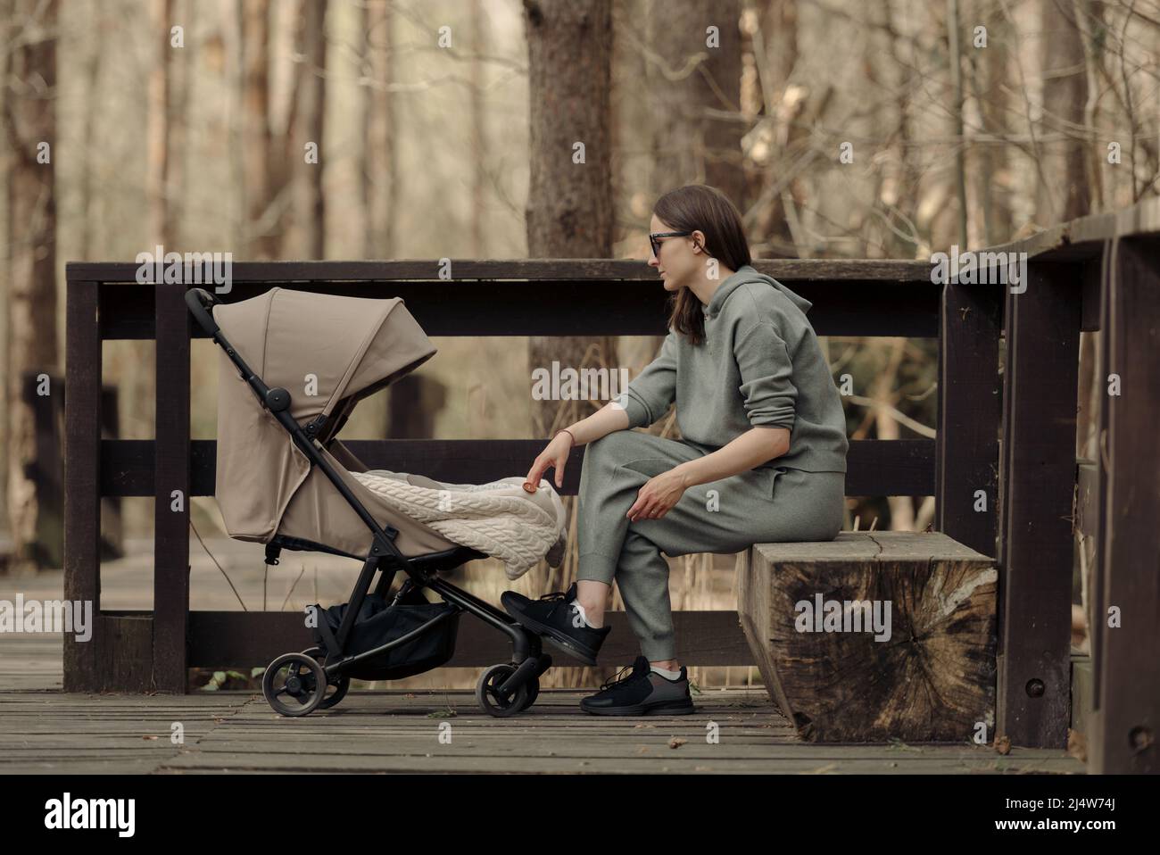 The mom is relaxing on the bench while her child is sleeping in the ...