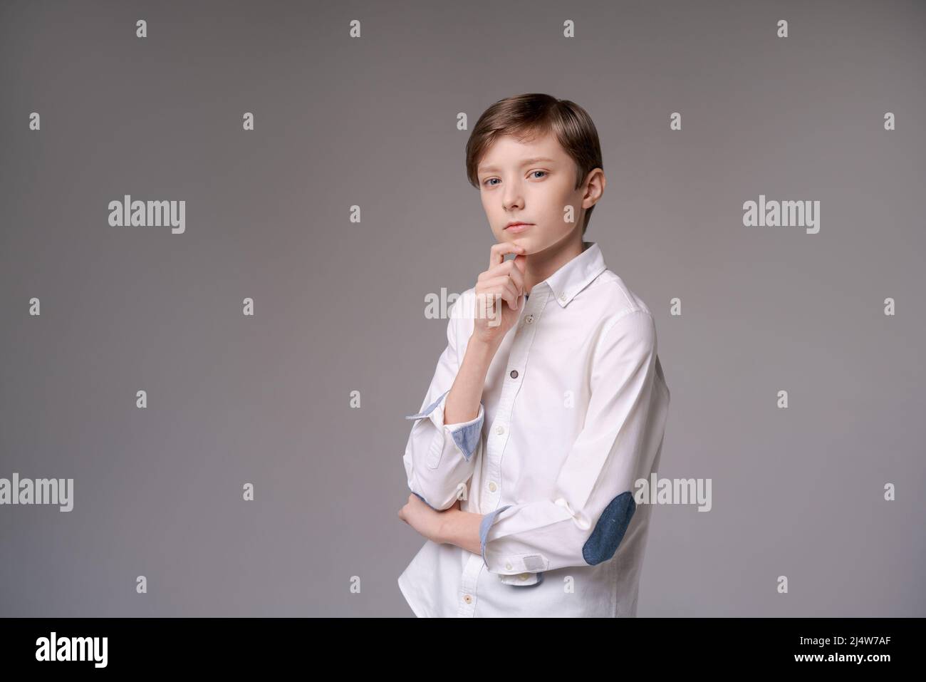 Thoughtful young teen man holding hand on chin indecision pose in white ...