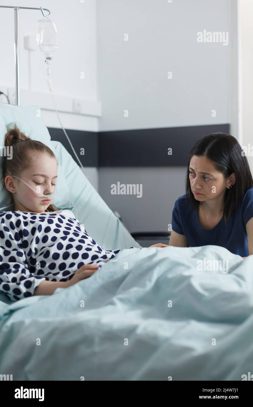 Anxious caring mother visiting hospitalized sick little girl while ...