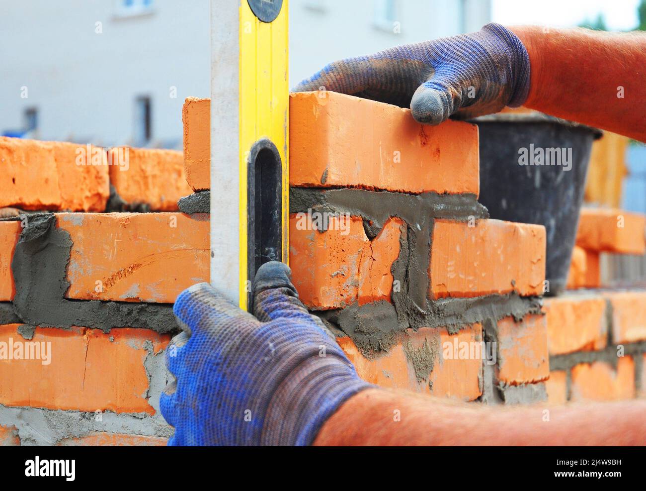 Building a brick wall. A mason person, bricklayer is checking with a ...